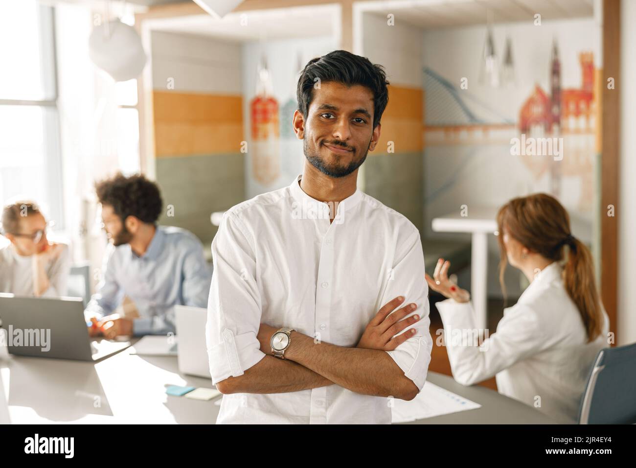 Portrait of smiling indian businessman standing in modern office on ...