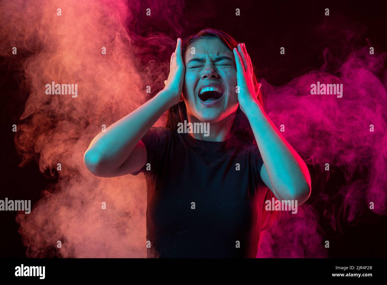 Emotional pain. Young dark hair woman shouting isolated over pink ...