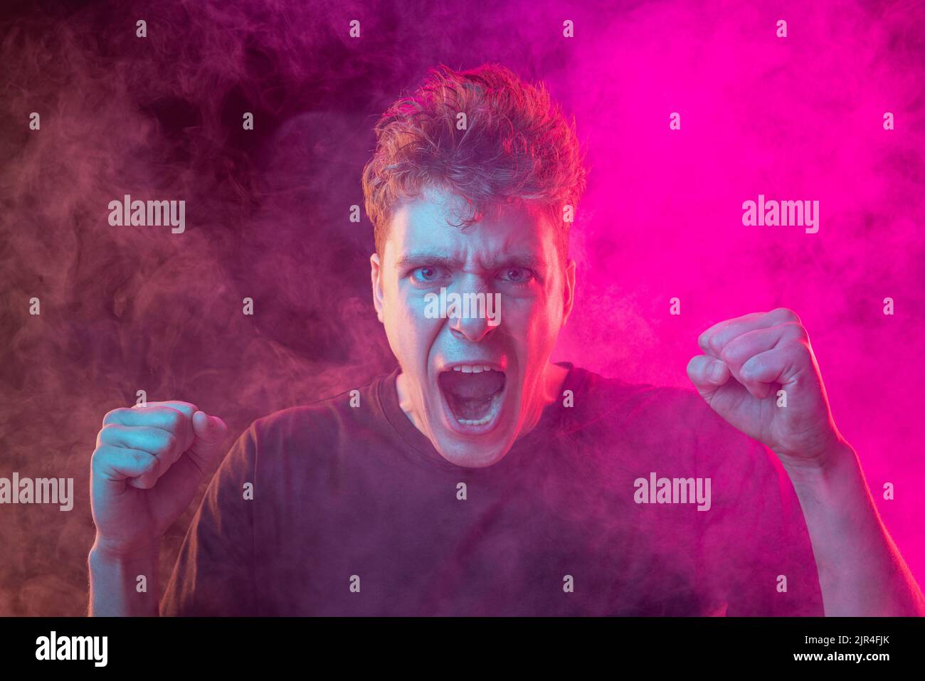 Shouting angry young man with bright emotions isolated over pink ...