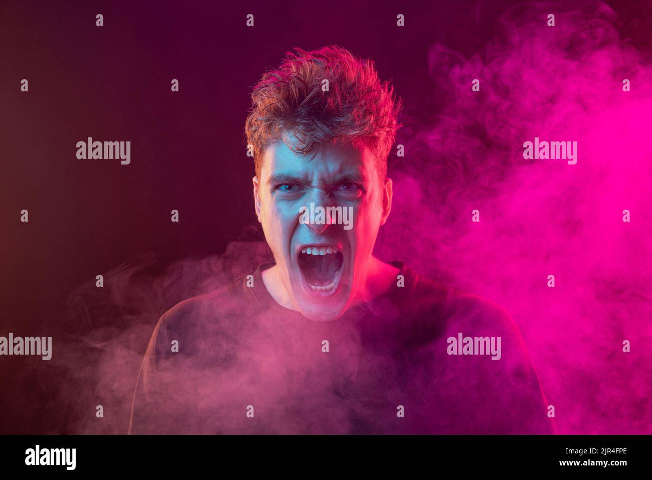 Shouting excited young man with bright emotions isolated over pink ...