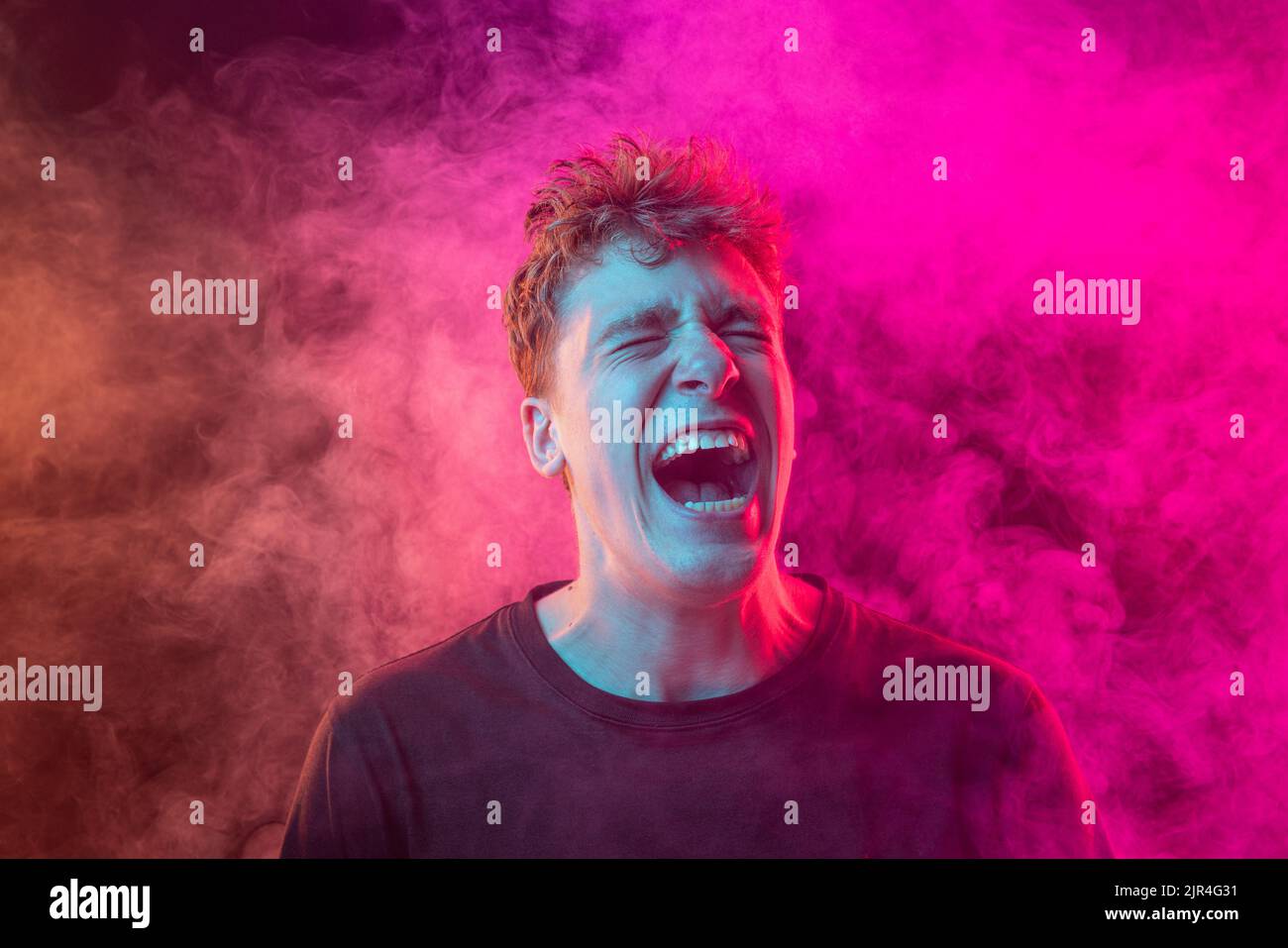 Shouting excited young man with bright emotions isolated over pink ...