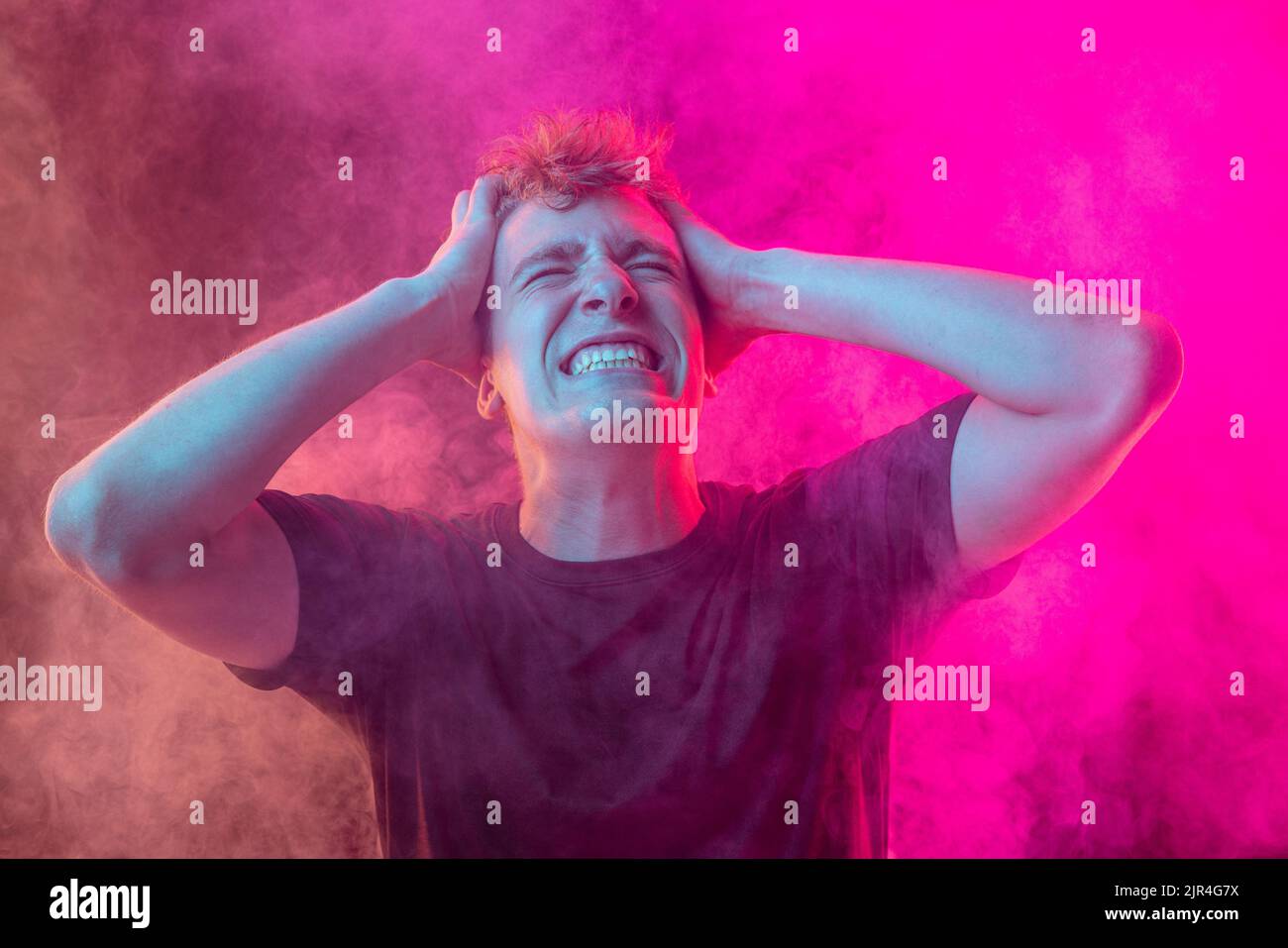 Emotional pain. Young man in deep emotional shock isolated over pink ...