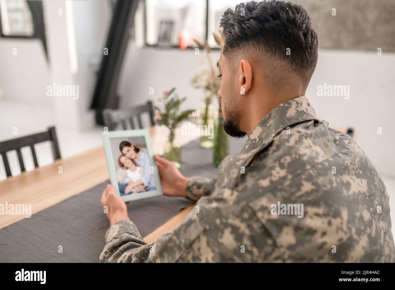 Army soldier looking at the framed family picture Stock Photo - Alamy