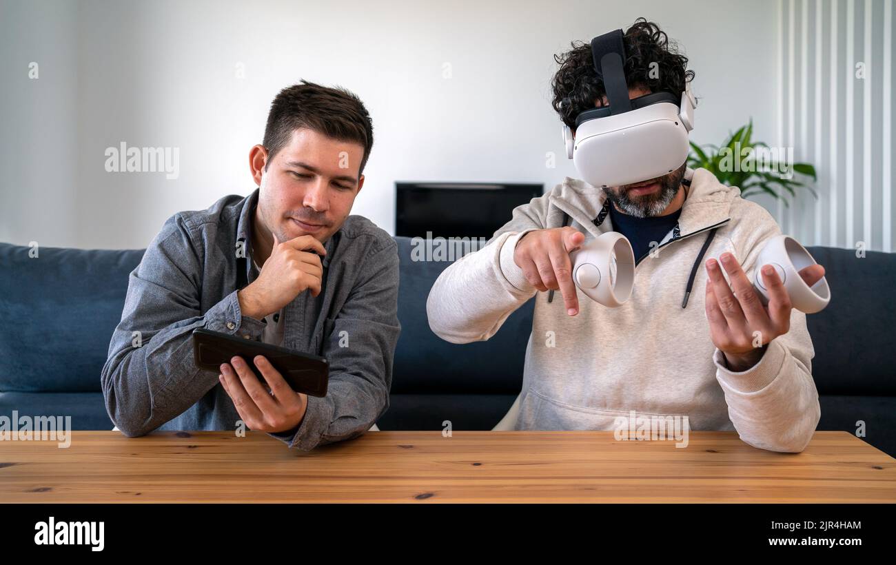Caucasian men enjoying virtual reality glasses while sitting at the ...
