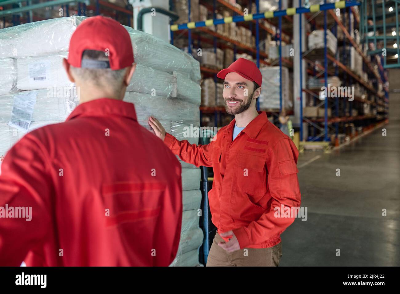 Team of storehouse loaders unloading goods together Stock Photo - Alamy