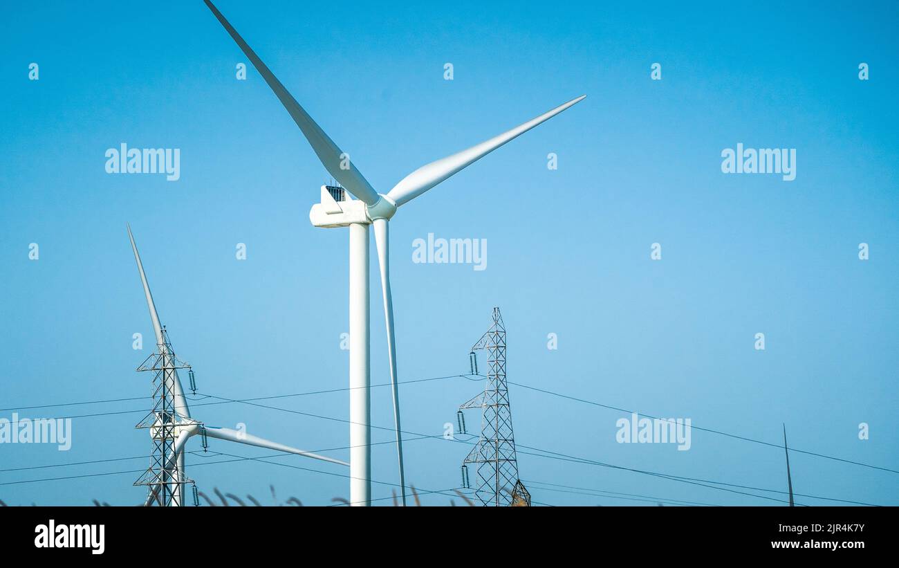 Wind turbine and pylons on a blue sky Stock Photo - Alamy