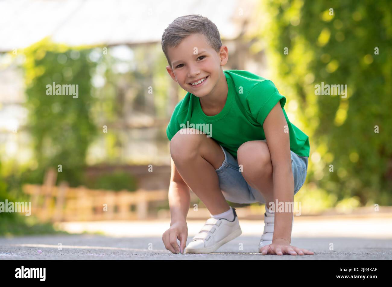 Boy with crayon crouched down to paint Stock Photo - Alamy
