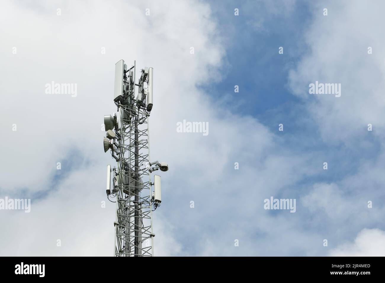 4G and 5G transmitters on a telecommunications tower. Cellular base station with white ...