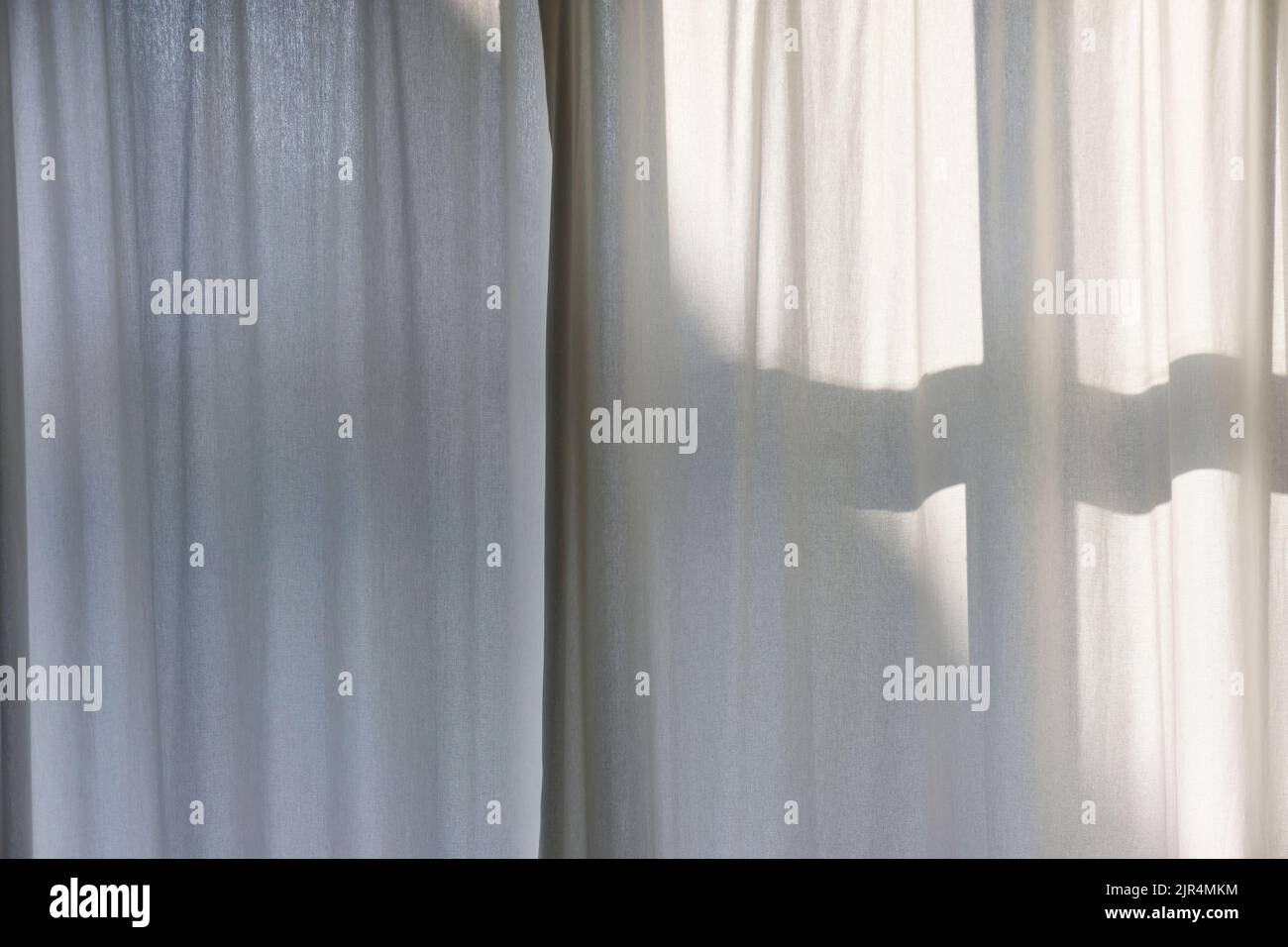 Morning sun shines through white transparent curtains with shadows from ...