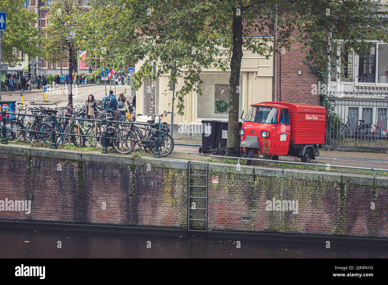 A classic red Piaggio APE three-wheeler parked on the street Stock ...