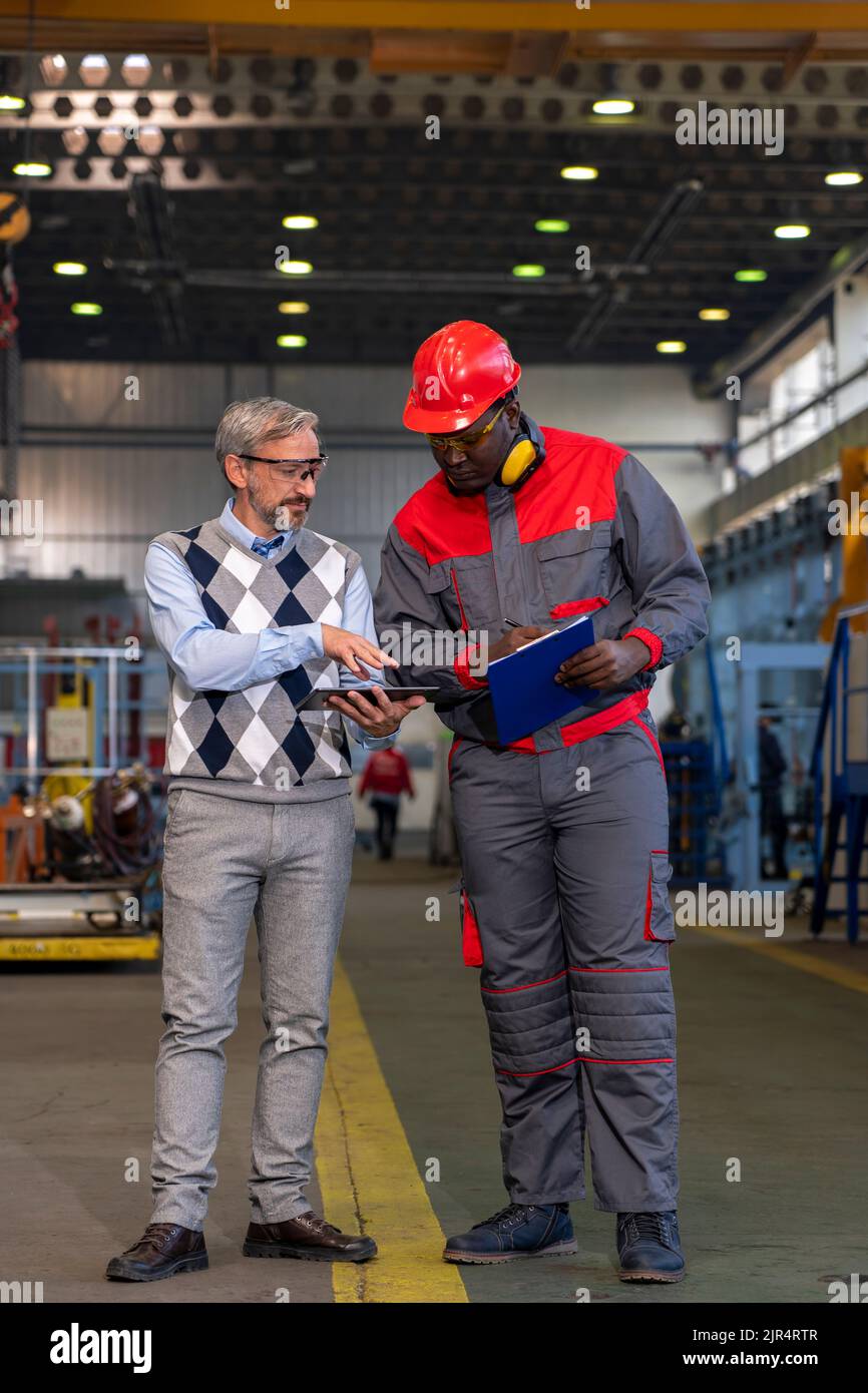 Multiracial Industrial Co-Workers Standing In A Factory And Talking ...