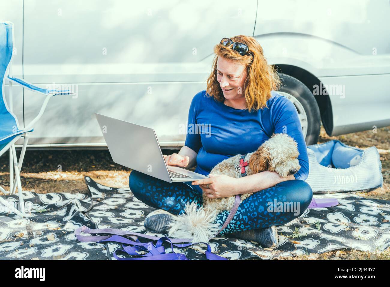 Adult woman working on laptop, sitting with her cockapoo puppy on the ...