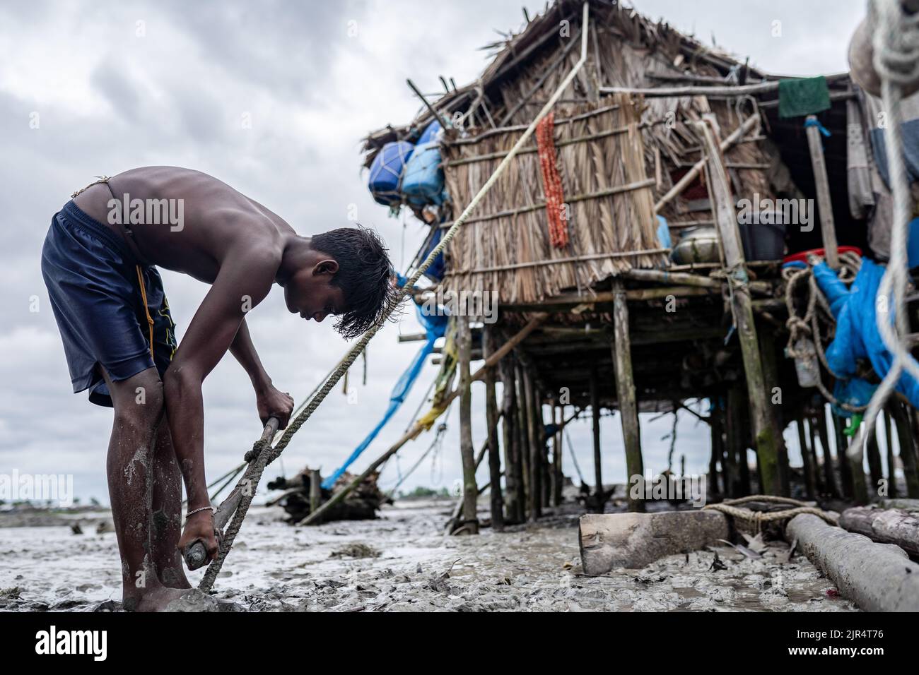 A boy is seen tying the rope to stable his house during the heavy storm ...