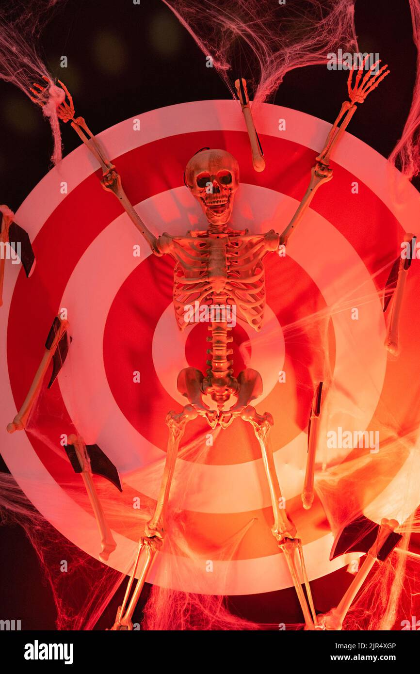 crucified skeleton with axes in red neon light on the target. Halloween ...