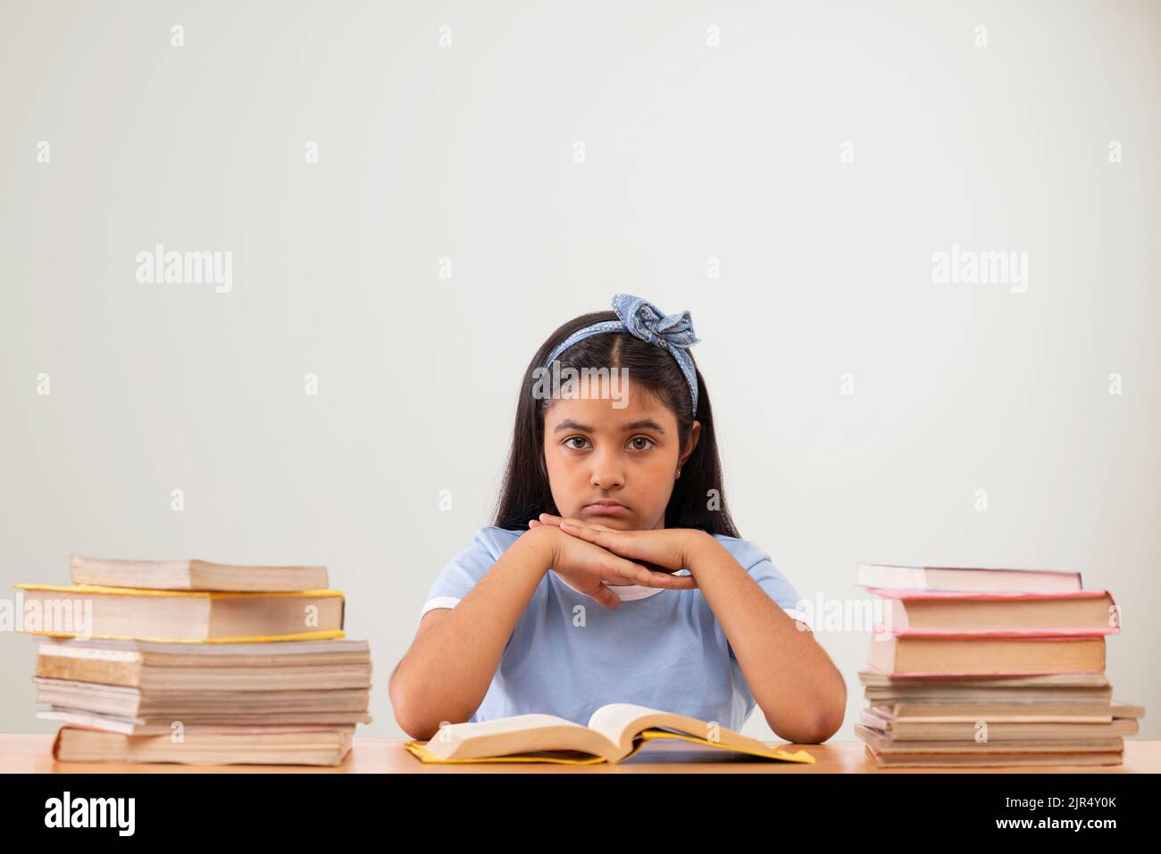 Girl with bored expression sitting between two stacks of books Stock ...