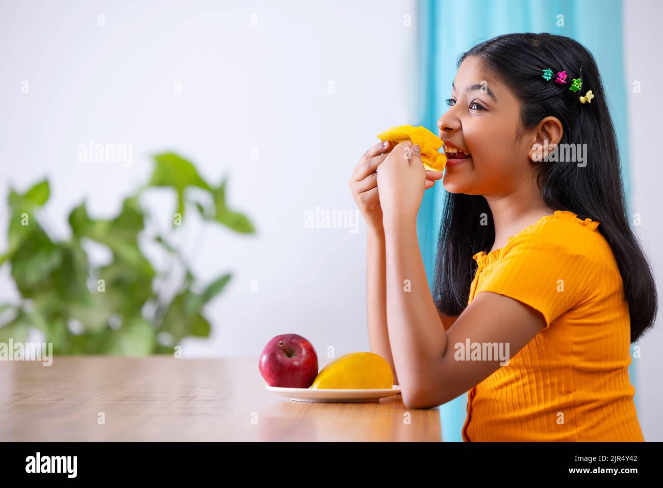 Portrait of cheerful girl holding a segmented slice of mango Stock ...
