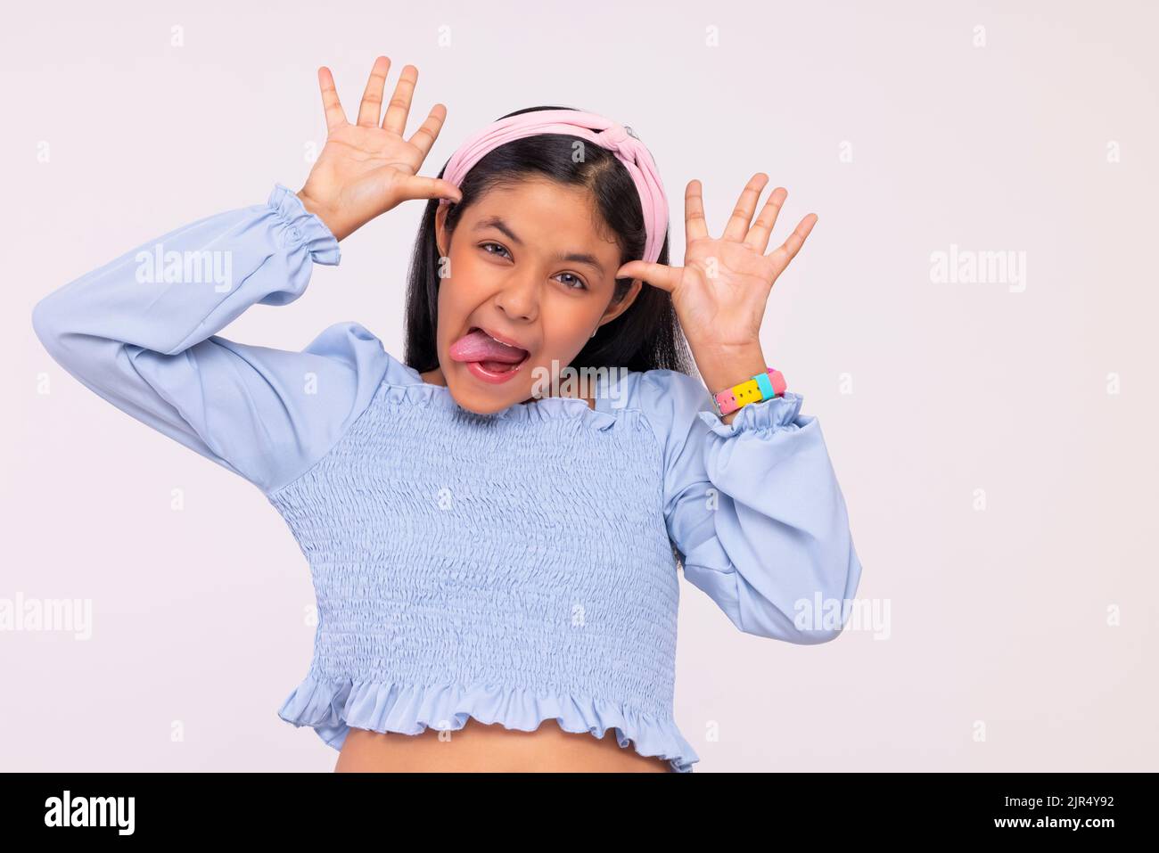 Portrait of little girl making funny face against plain background ...