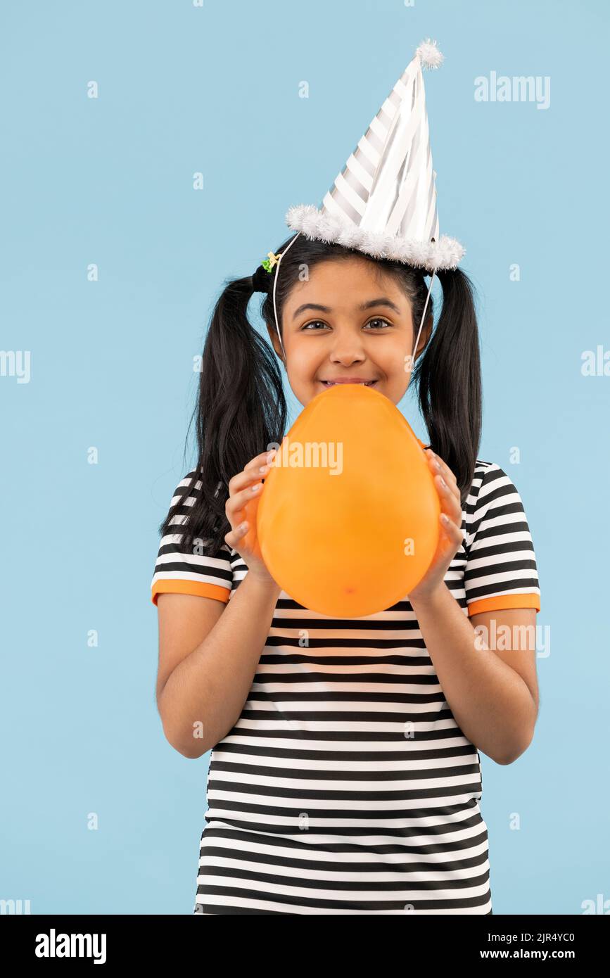 Little girl blowing yellow balloon against blue background Stock Photo ...