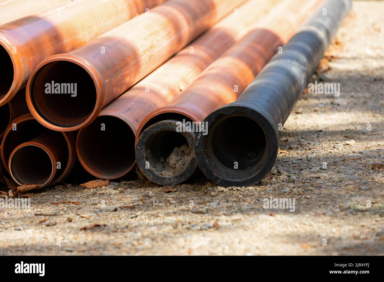 Laying down orange PVC drainage pipes into the ground Stock Photo - Alamy