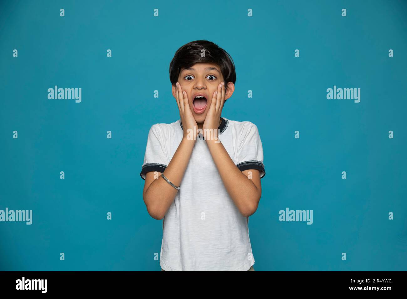 Portrait of shocked boy standing against blue background Stock Photo ...