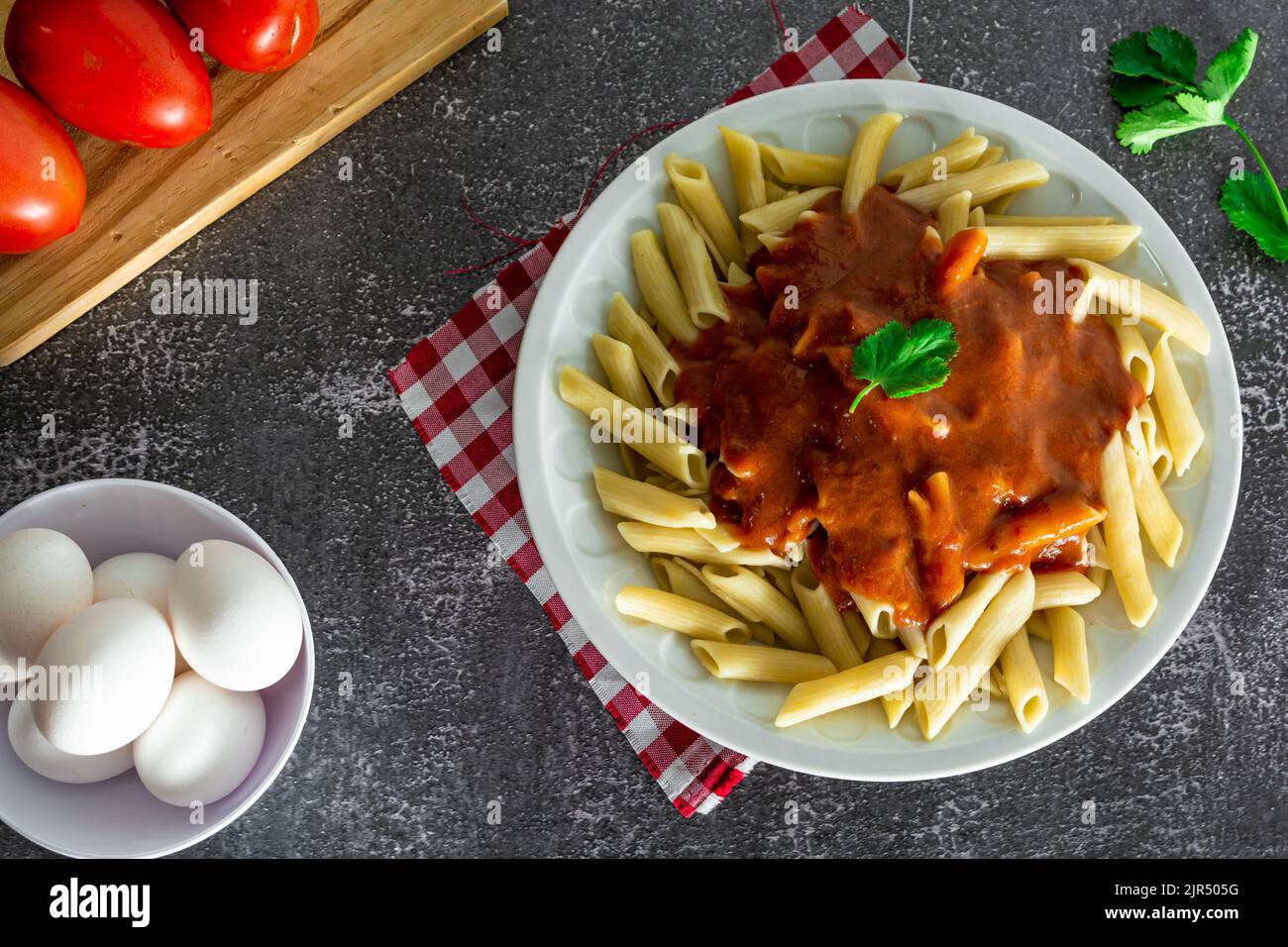 typical italian penne pasta on dark stone background with tomato sauce ...