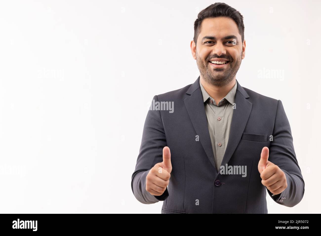 Portrait of a cheerful young businessman in formal outfit showing ...