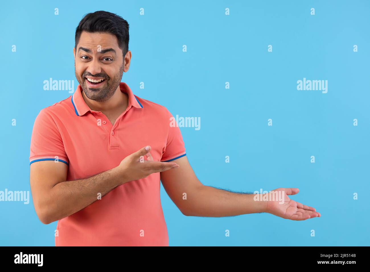 Smiling young man pointing sideways against blue background Stock Photo ...