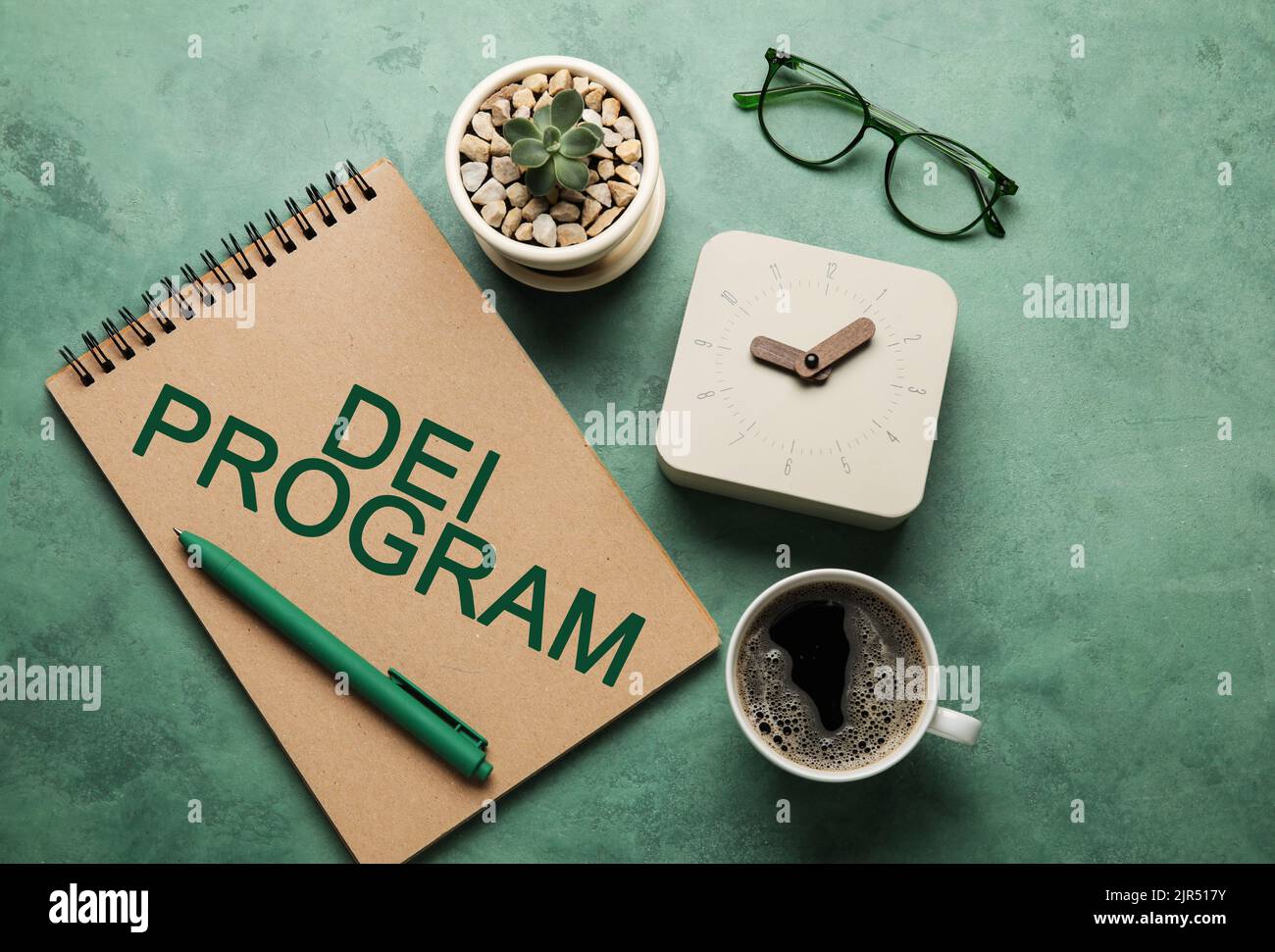 Notebook with text DE and I (diversity, equity, inclusion) program, pen, alarm clock, eyeglasses ...