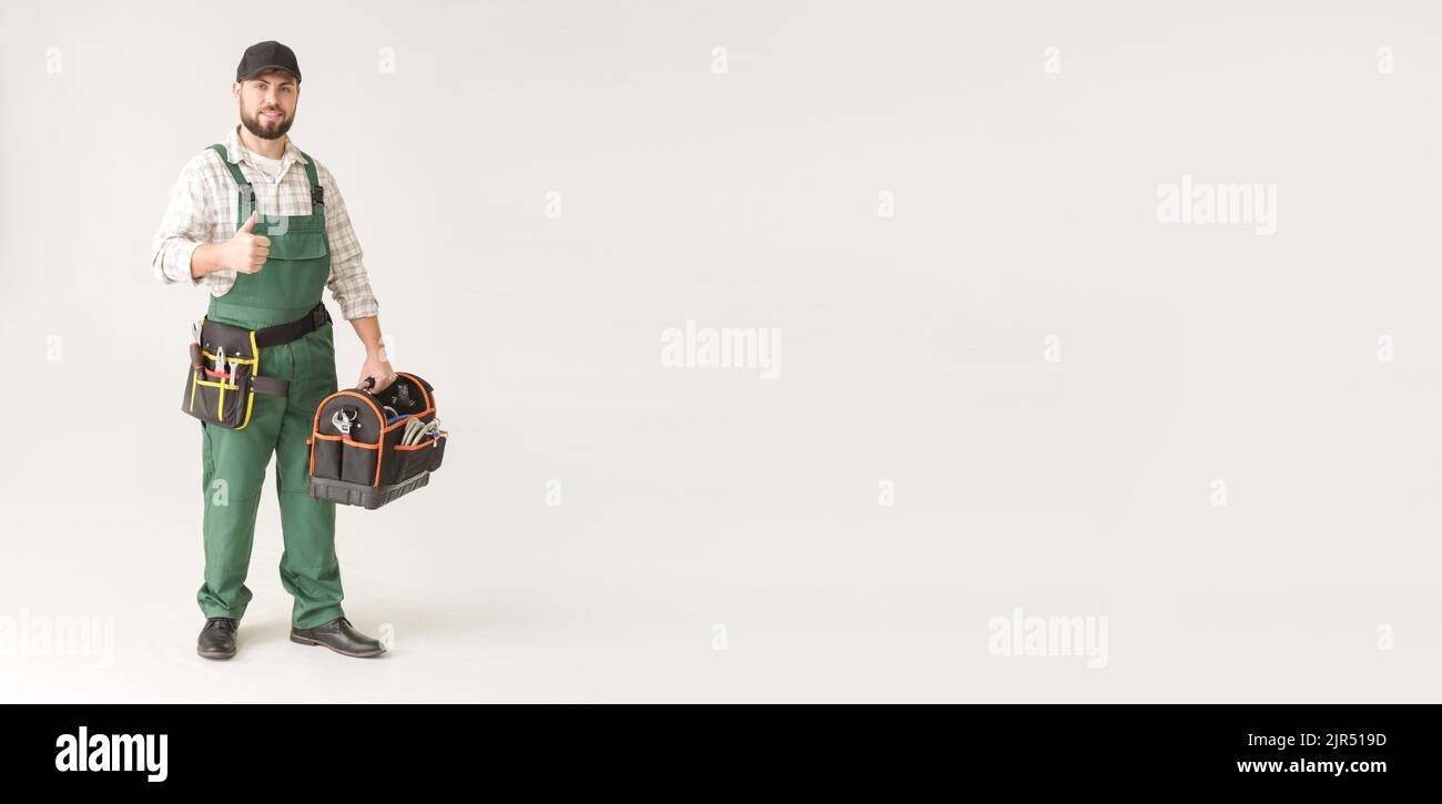 Handsome worker showing thumb-up on light background with space for ...