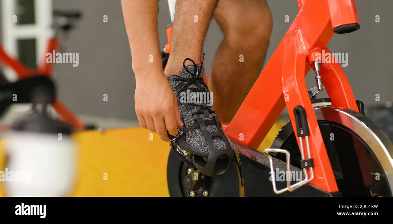 Young man training on exercise bike in gym, closeup Stock Photo - Alamy