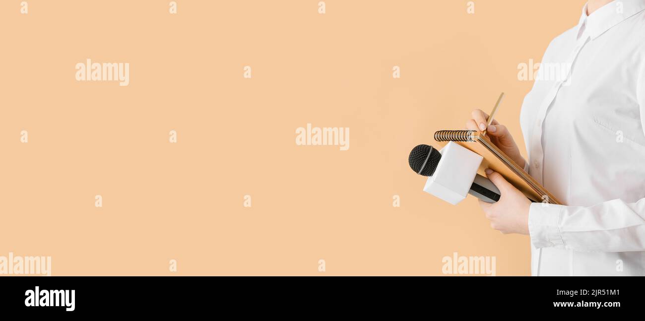Journalist with microphone and notebook on beige background with space ...