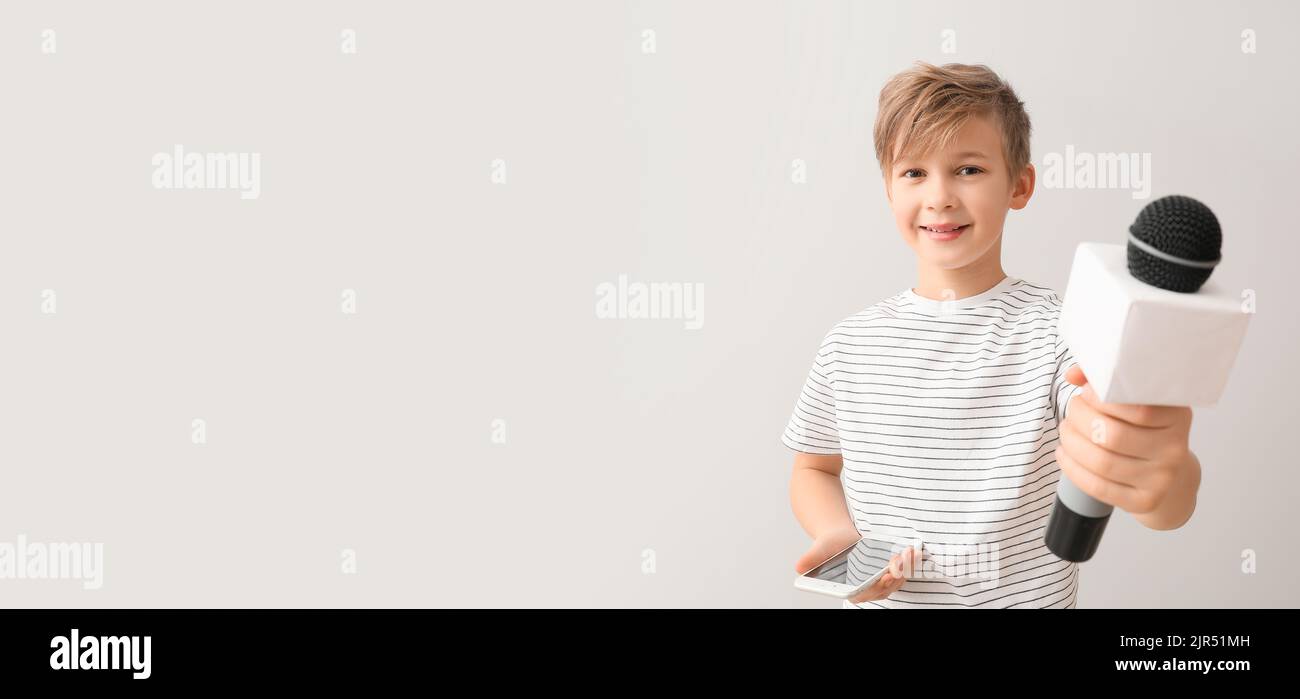 Little journalist with microphone on light background with space for ...