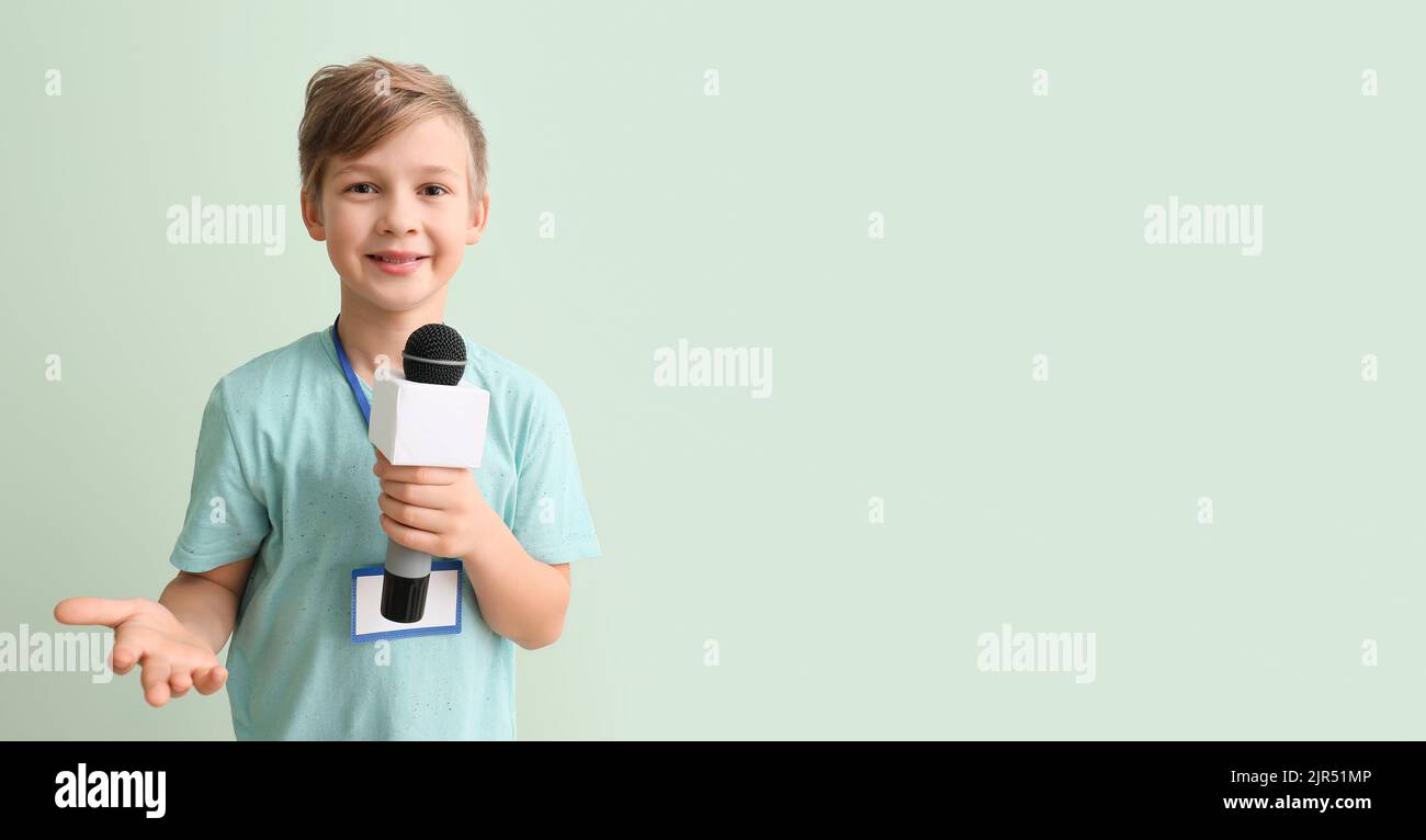 Little journalist with microphone on light green background with space ...