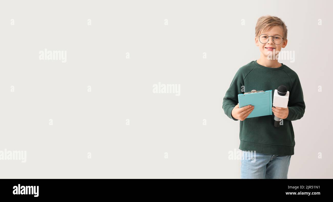 Little journalist with microphone on light background with space for ...