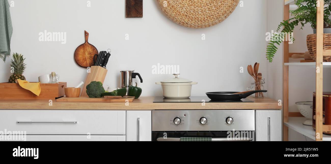 Modern electric stove with cookware and utensils in light kitchen Stock ...