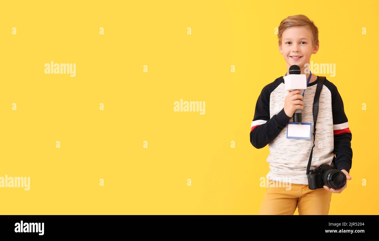 Little journalist with microphone and photo camera on yellow background ...