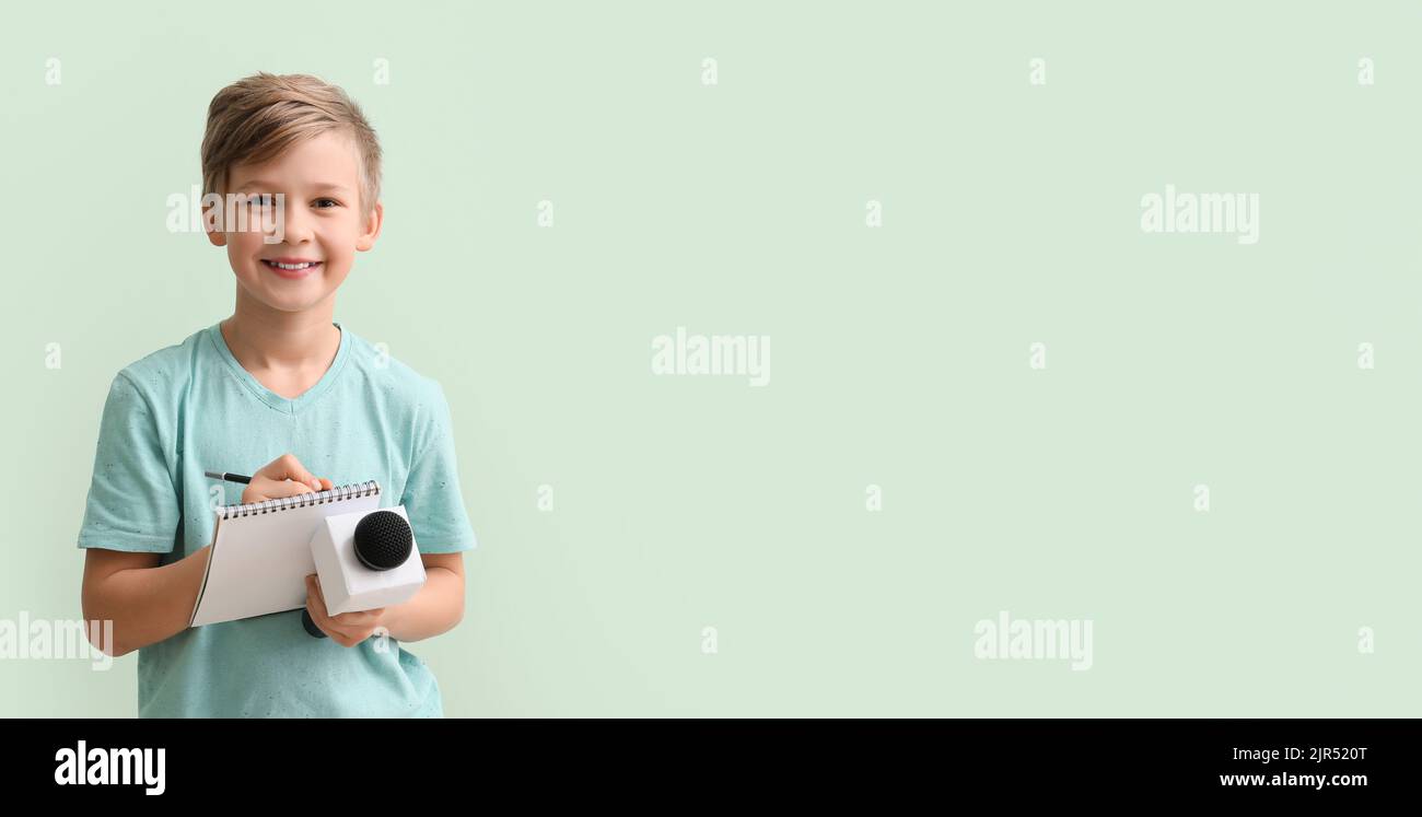 Little journalist with microphone and notebook on light color ...