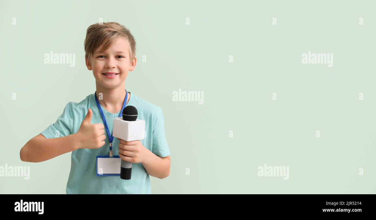 Little journalist with microphone showing thumb-up on color background ...