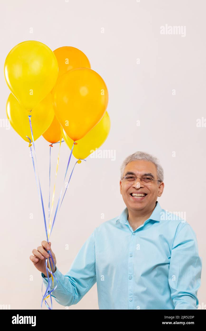 Happy senior man looking at camera with smile with holding bunch of ...