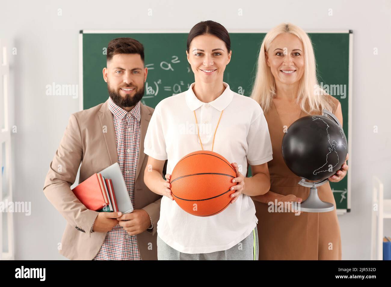 Teachers with books, ball and globe in classroom Stock Photo - Alamy