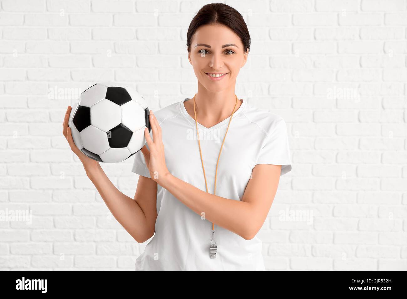 Beautiful PE teacher with ball on white brick background Stock Photo ...