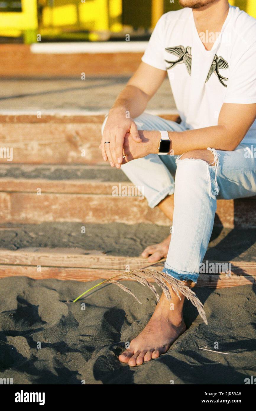 Young barefoot man sitting on the wooden steps Stock Photo - Alamy