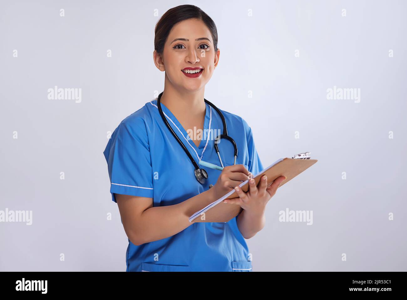 Portrait of a female nurse writing down patient information standing ...