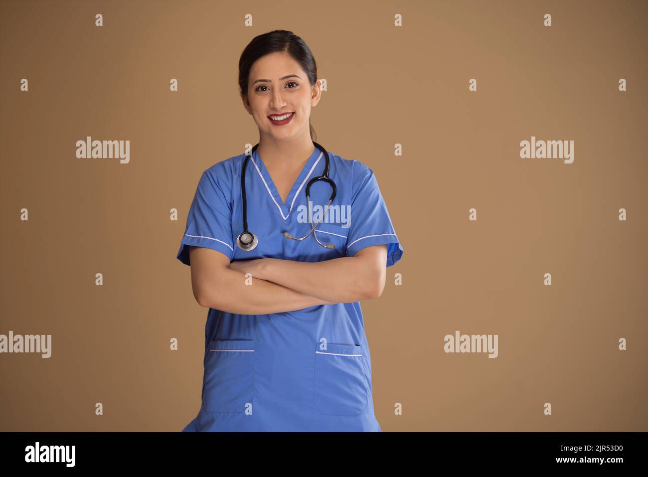 Portrait of a female nurse in blue scrubs with a stethoscope around her ...