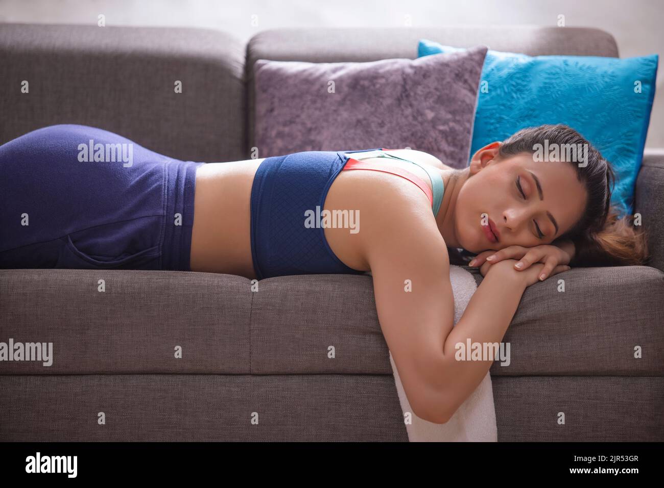 Tired woman lying down on sofa after exercise Stock Photo - Alamy