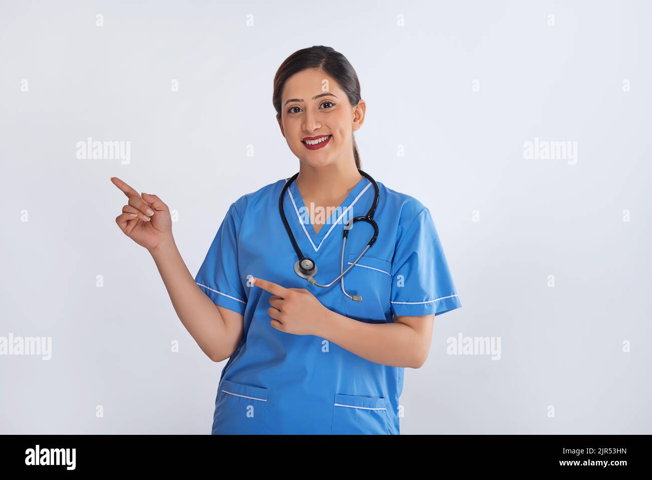 Portrait of a cheerful female nurse pointing sideways Stock Photo - Alamy