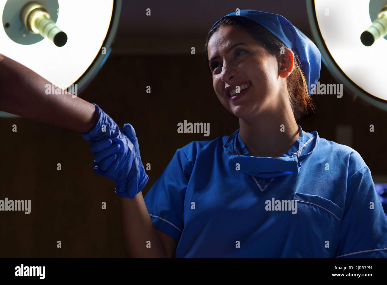 Portrait of happy female nurse shaking hand with colleague after ...