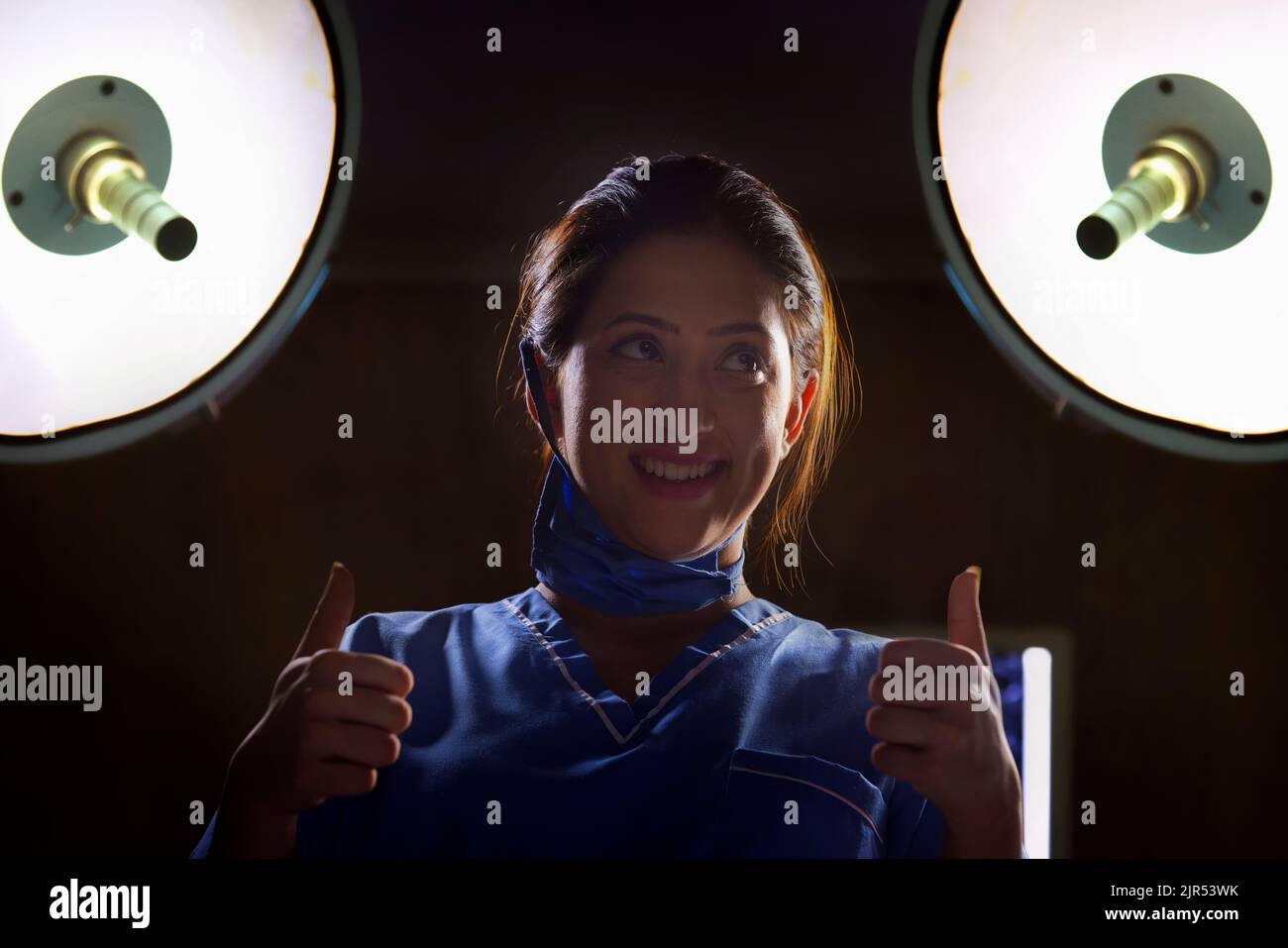 Portrait of cheerful female nurse after successful surgery in operating ...