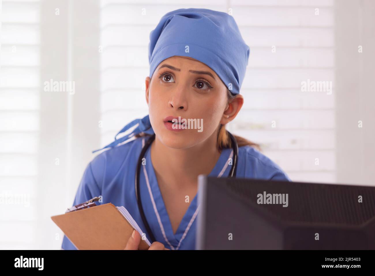 Close-up of female nurse holding clipboard and using computer in ...