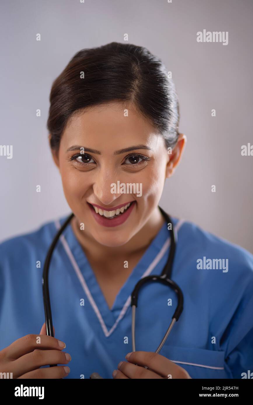 Close-up portrait of a young cheerful female nurse against plain ...